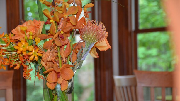 Um vaso com flores laranja sobre uma mesa.