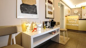 Uma área de recepção com balcão branco, um relógio e uma placa com a inscrição "VATICAN RELAX GUESTHOUSE".