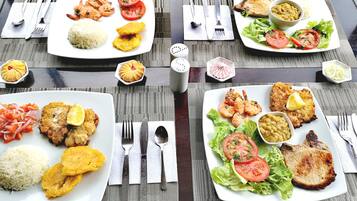 Uma mesa posta com pratos de comida, talheres e acompanhamentos.