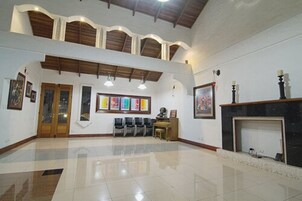 Um hall amplo com teto alto, lareira e várias obras de arte emolduradas nas paredes.