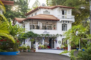 Um edifício branco com telhado de telhas vermelhas, varanda e um letreiro que diz 'HOTEL'.