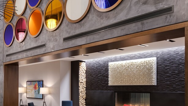 Um interior moderno com uma área de estar central, lareira e uma parede com espelhos circulares.