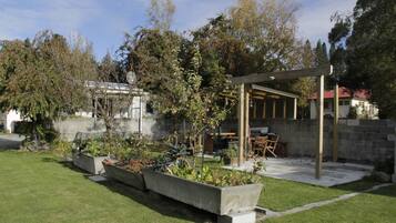 Um quintal com pérgola, área de estar externa e um jardim com diversas plantas.