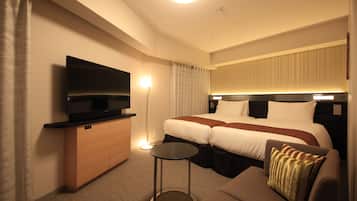 Quarto de hotel com cama, televisão, mesa pequena e sofá.