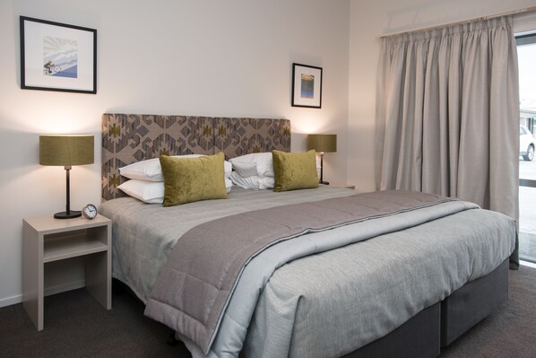 Quarto de hotel bem arrumado, com uma cama, duas mesas de cabeceira e duas luminárias.