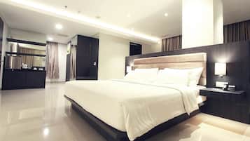 Quarto de hotel moderno com uma cama grande, banheiro separado e área de cozinha compacta.