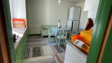 Uma cozinha compacta com área de refeições, geladeira e tapete estampado.