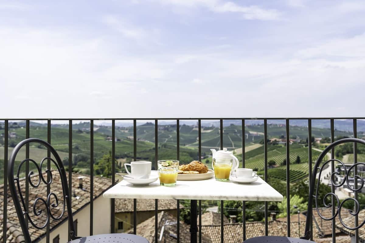 Mesa de varanda com itens de café da manhã e vista para colinas ondulantes.