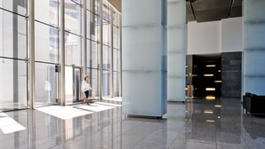 Um lobby moderno com grandes portas de vidro, piso polido e área de estar.