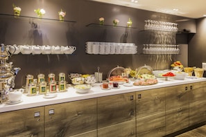 Disposição de buffet com diversos alimentos e utensílios.