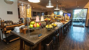 Buffet de café da manhã com diversos alimentos e um aviso indicando capacidade para 93 pessoas.