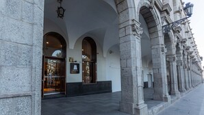 Uma fachada de pedra, portas em arco e uma série de colunas na entrada de um edifício.