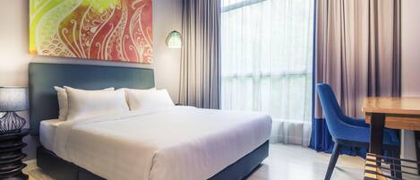 Quarto de hotel com uma cama grande, uma escrivaninha e uma cadeira.