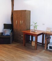 Quarto com armário de madeira, mesa, cadeira e uma pequena planta.