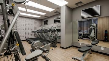 Uma academia moderna com esteiras, aparelhos de musculação e um espelho grande refletindo os equipamentos.