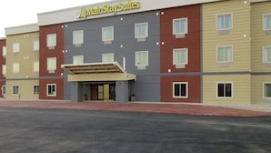 Um hotel MainStay Suites com fachada moderna, vários andares e entrada coberta.