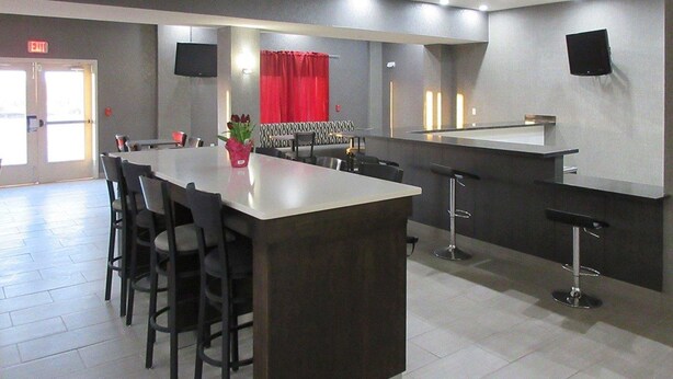 Uma cozinha moderna com ilha central, banquetas de bar e uma televisão de tela plana fixada na parede.