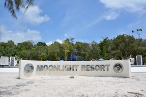 Placa do Moonlight Resort, com céu claro e árvores ao fundo.