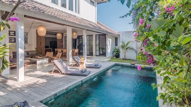 Uma área com piscina, cadeiras de descanso e um deck de madeira.