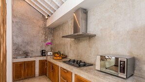 Uma cozinha com armários de madeira, um exaustor de aço inoxidável, micro-ondas e uma fruteira sobre o balcão.