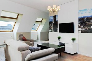 Uma sala de estar moderna com um sofá, uma mesa de centro, uma TV na parede e claraboias.