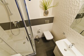Uma casa de banho moderna com chuveiro em cabine de vidro, sanita e lavatório.