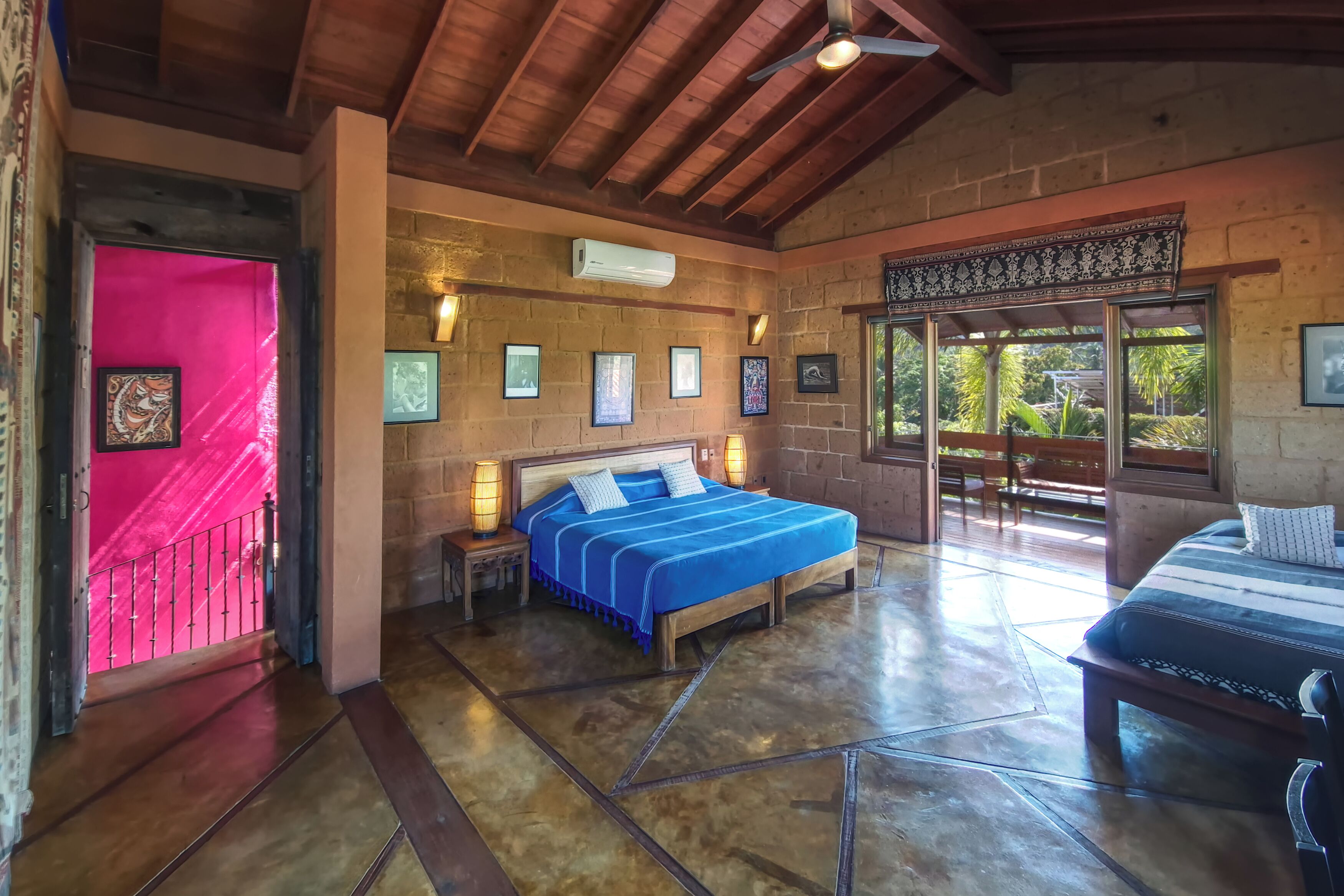 Um quarto espaçoso com uma cama grande, outra cama, uma varanda com vista e teto de madeira.