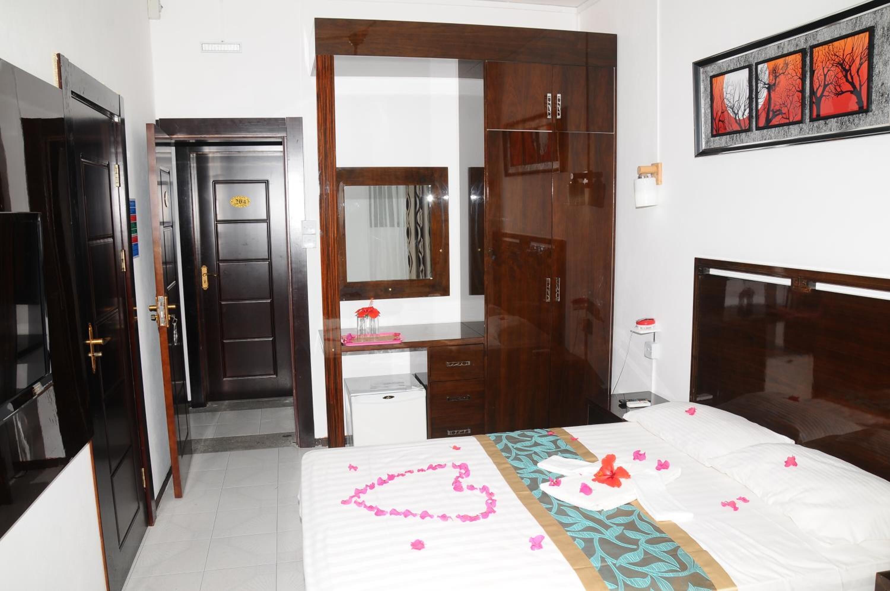 Quarto de hotel com cama, guarda-roupa, escrivaninha e espelho.