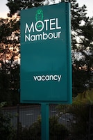 Uma placa verde para um motel, com o nome 'Motel Nambour' e um aviso de 'vagas'.