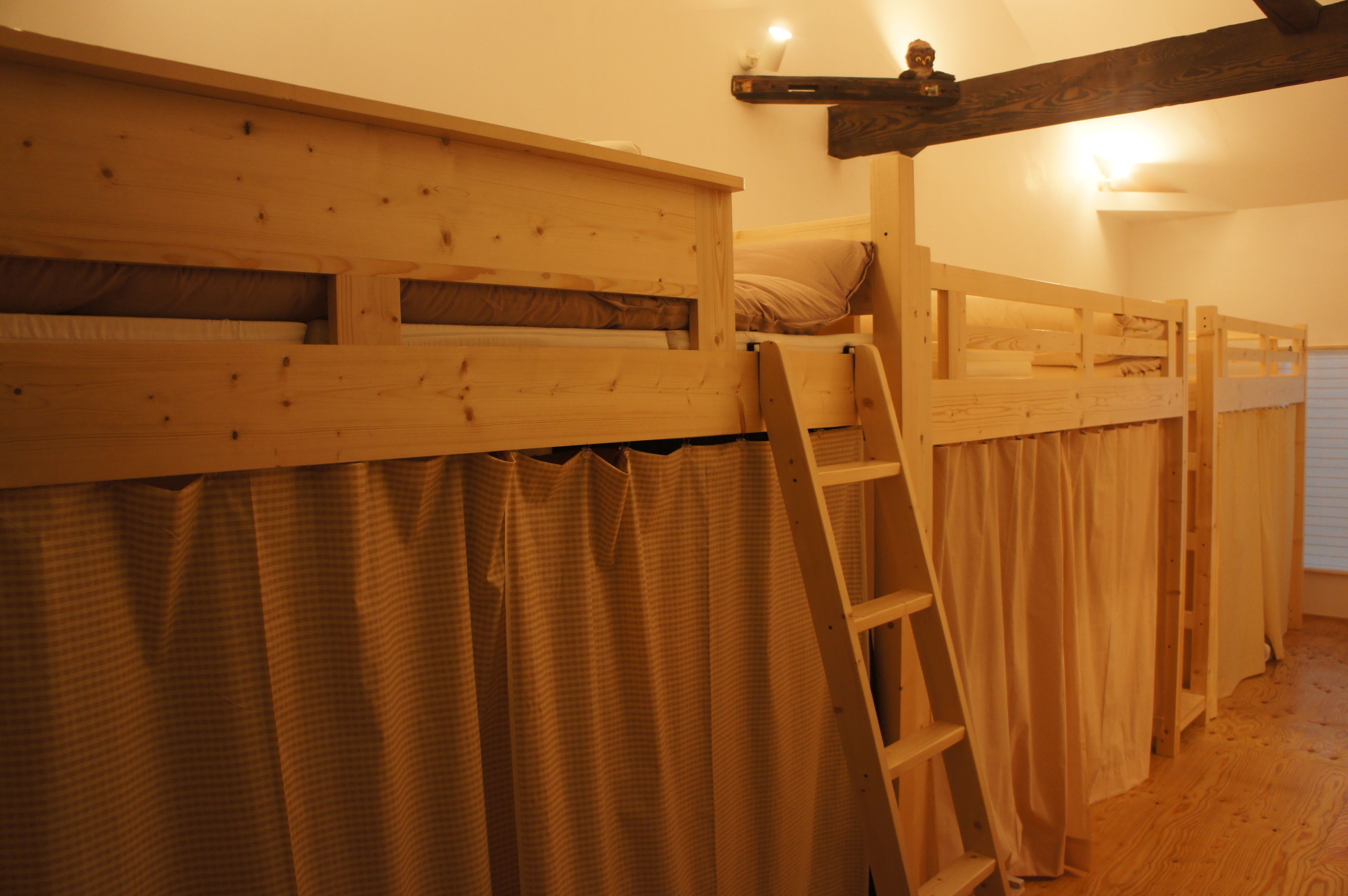 Quarto com uma cama beliche de madeira, uma escada e uma cortina.