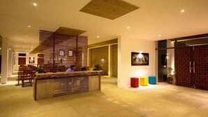 Um lobby moderno com balcão de recepção, área de estar e um amplo teto de ripas de madeira.