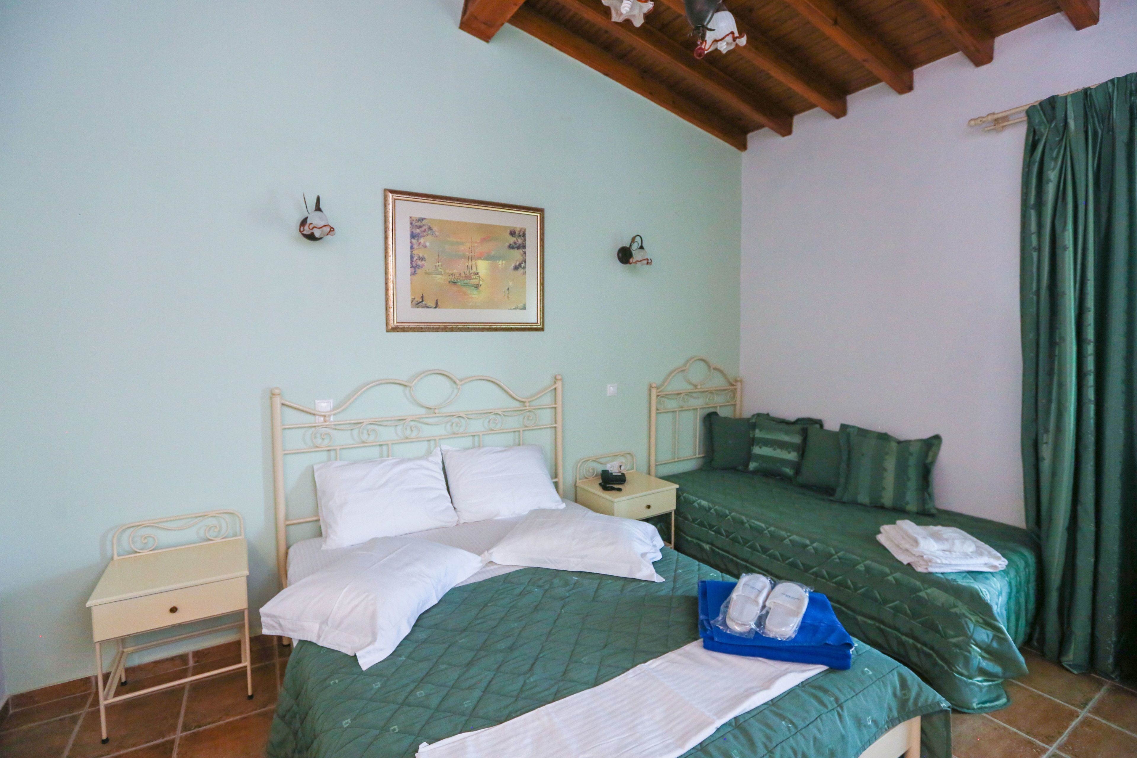 Quarto com duas camas, uma mesa de cabeceira, um quadro e uma cesta azul com toalhas.