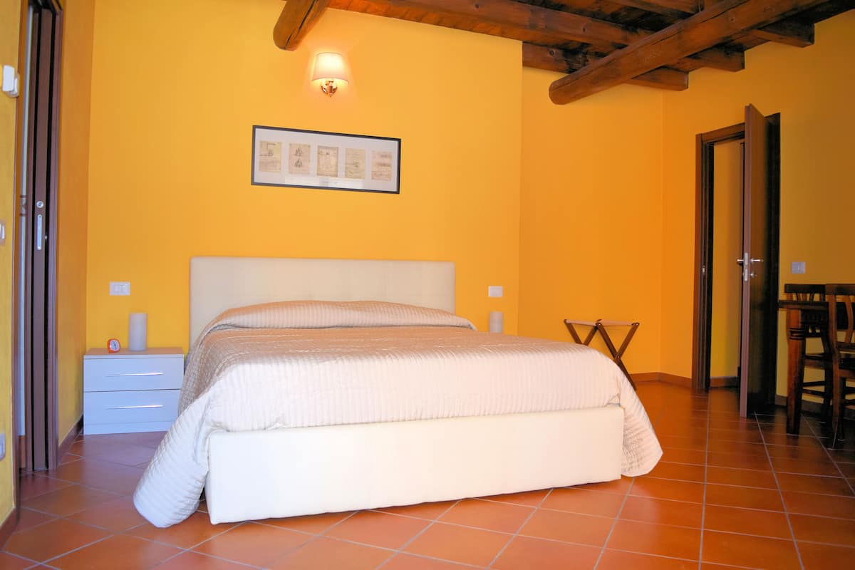 Quarto com uma cama, mesa de cabeceira, cadeira e porta.