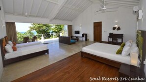 Um quarto espaçoso com uma cama grande, um sofá e uma varanda com vista para o mar.