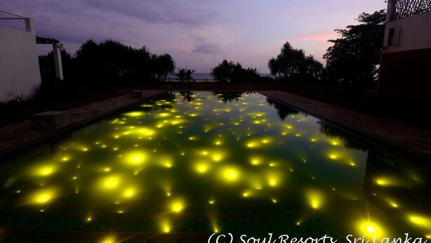 Piscina iluminada com luzes amarelas no Soul Resorts, Sri Lanka.