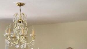 Quarto com um candelabro, uma penteadeira com espelho e uma cama.