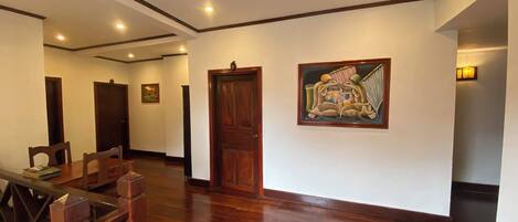 Um corredor com piso de madeira, uma porta de madeira e uma obra de arte emoldurada na parede.