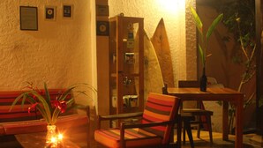 Um quarto acolhedor com uma mesa de madeira, um banco estofado e um prancha de surf encostada na parede.