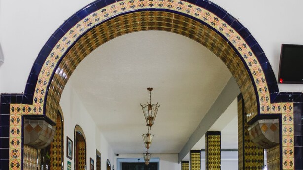 Um corredor com um arco revestido de azulejos com a inscrição 