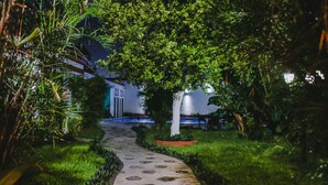 Um caminho que leva a um edifício rodeado por vegetação exuberante e um jardim bem cuidado.