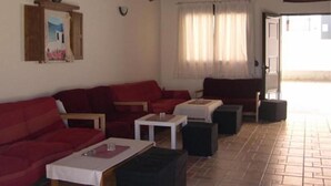Sala de estar com um sofá vermelho, uma mesa pequena e uma janela com cortinas.