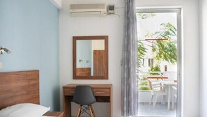 Quarto de hotel com cama, secretária, cadeira, espelho e varanda com mesa e cadeiras.