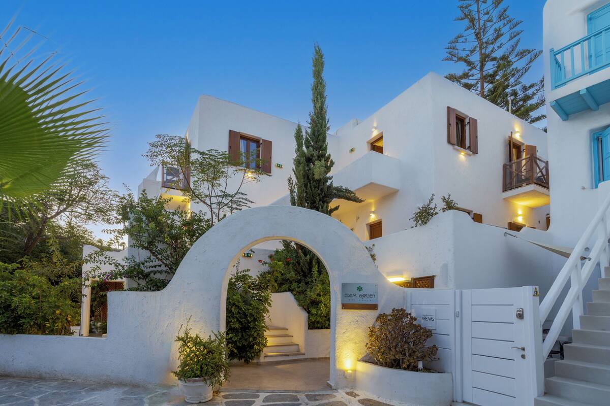 Um edifício branco com escadaria, um arco e uma placa com a inscrição 'Eden Garden'.