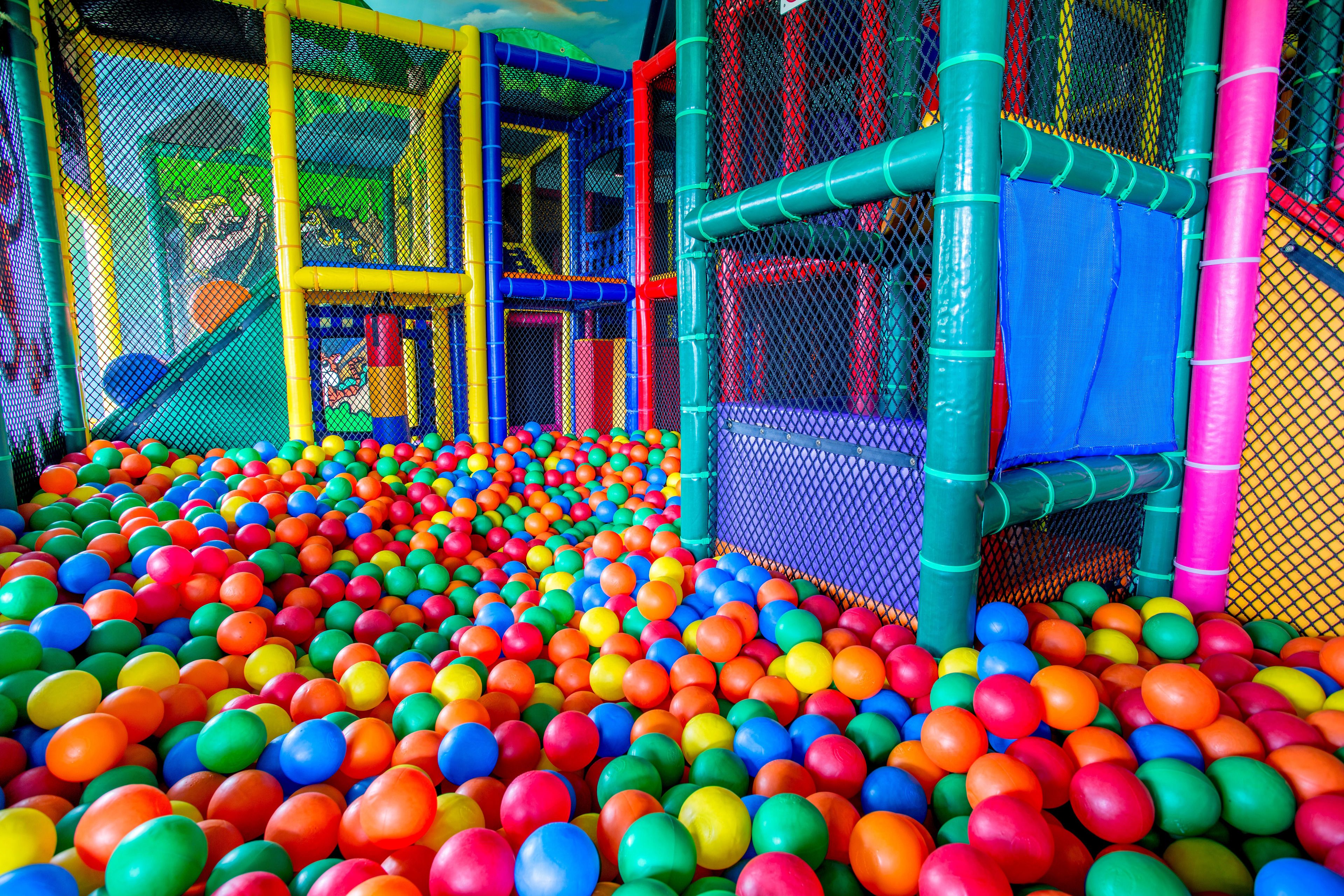 Uma área de recreação interna colorida com uma piscina de bolinhas e diversas estruturas de lazer.