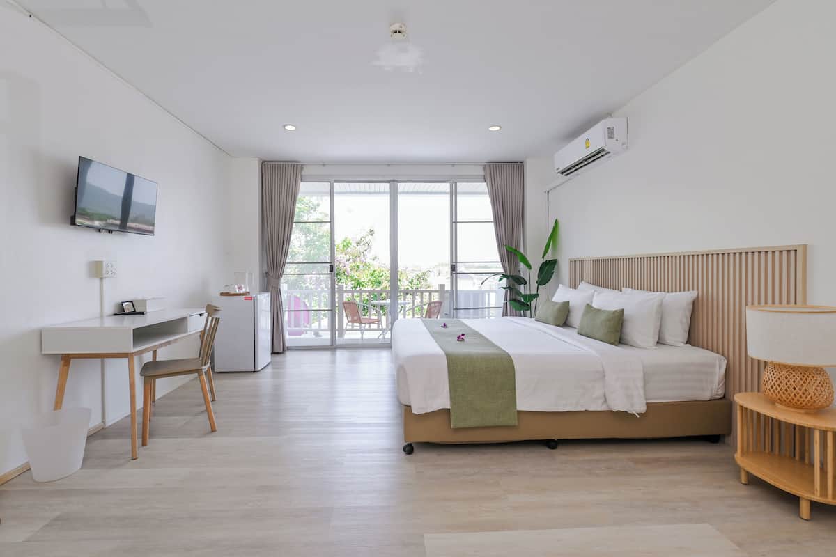 Quarto de hotel moderno com cama, escrivaninha, cadeira e televisão.