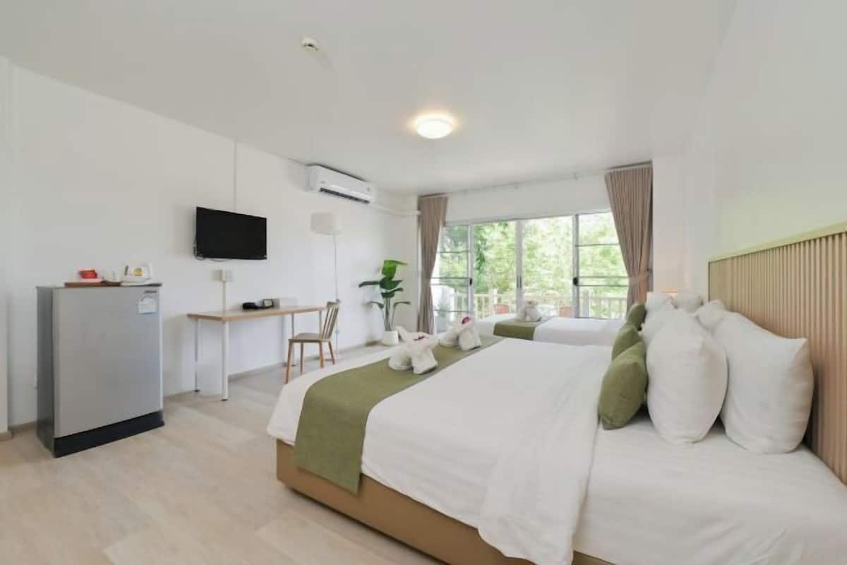 Quarto de hotel com cama, escrivaninha e televisão.