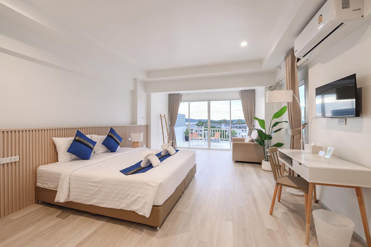 Quarto de hotel com cama, escrivaninha, televisão e varanda com vista.