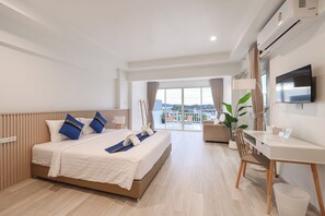Quarto de hotel com cama, escrivaninha, televisão e varanda com vista.