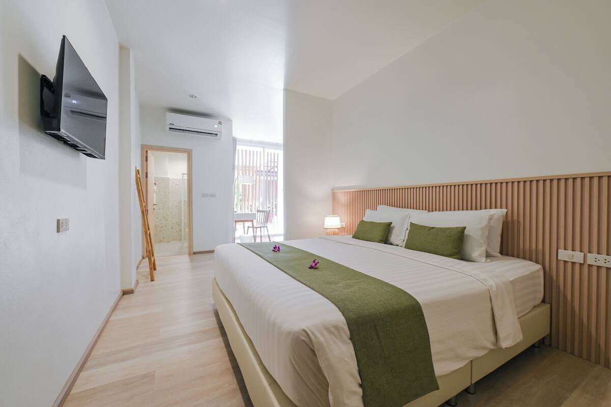 Quarto de hotel com cama, televisão na parede, ar condicionado e janela com vista.