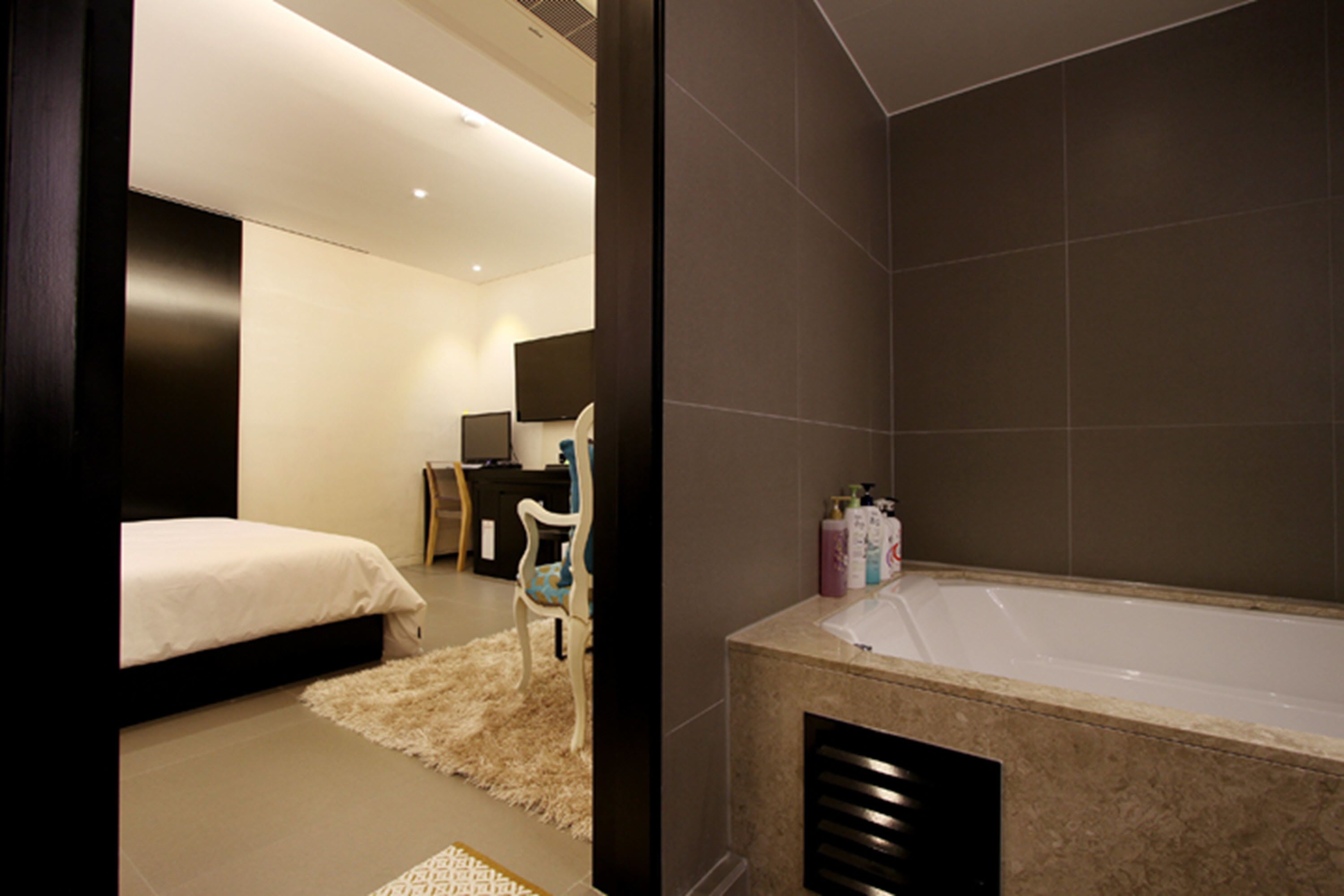 Quarto moderno com uma cama grande, uma escrivaninha e um banheiro com banheira.